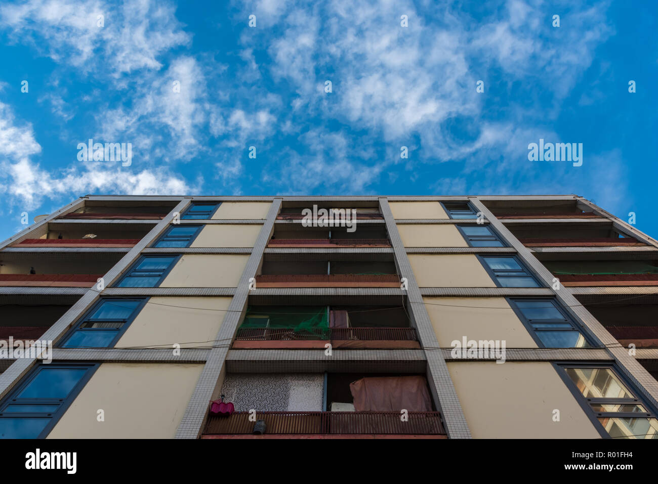 The apartment building on the edge of the road under a blue fall sky ...