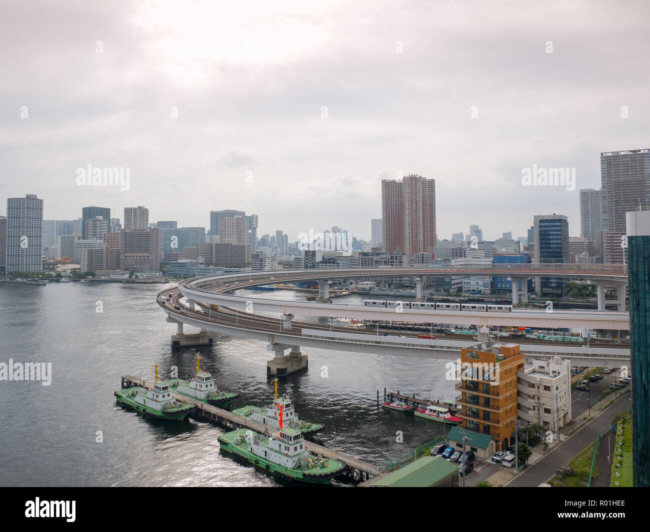 Modern highway with automobiles and train leading to a bridge. Rainbow ...
