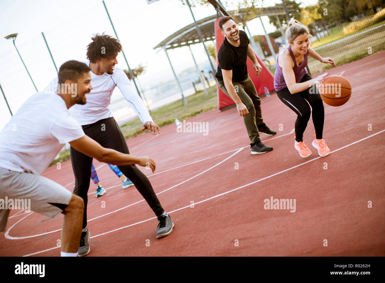 Group of multiethnic young people playing basketball on court Stock ...