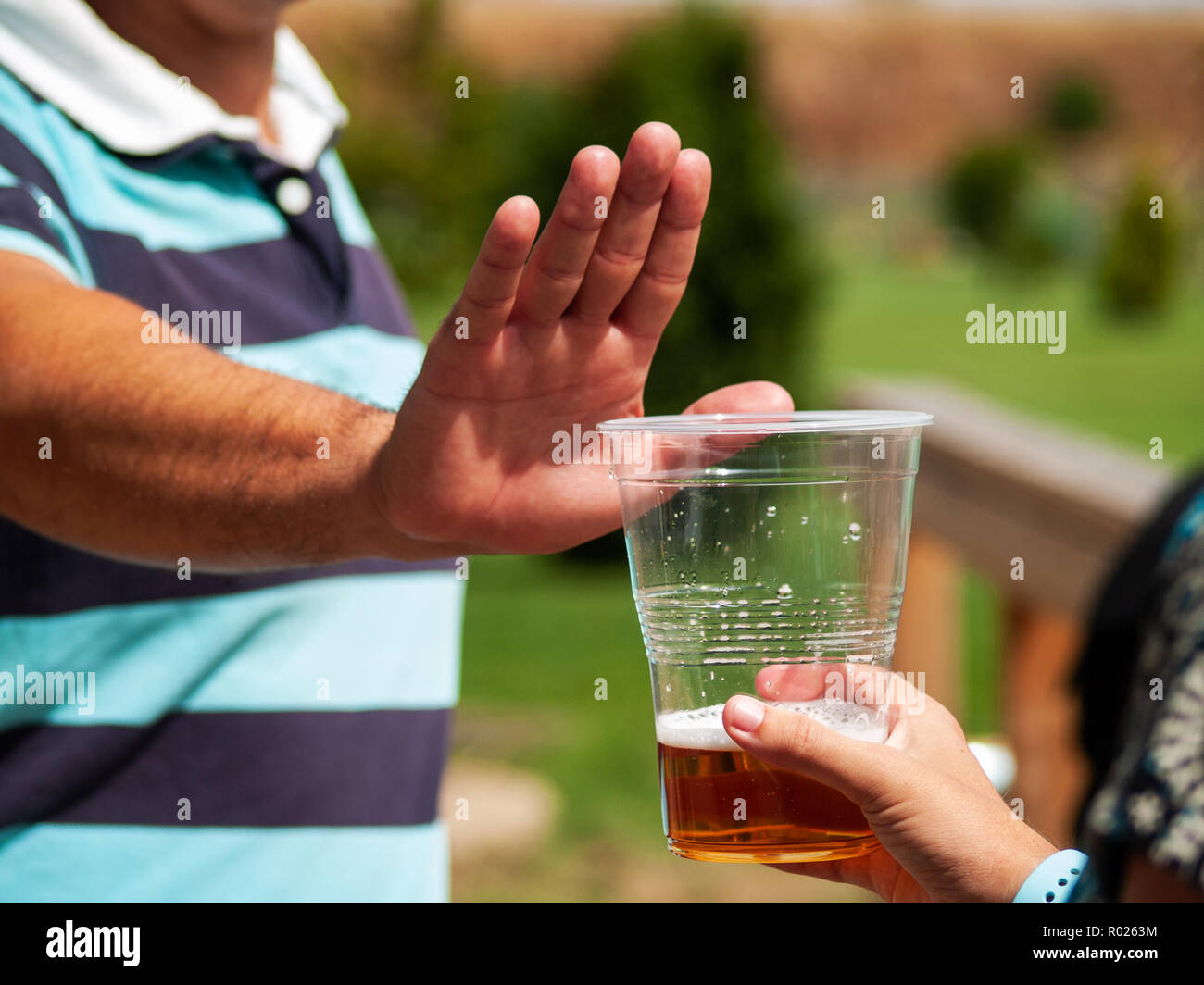 Stop alcohol concept. A man making a stop gesture to a glass of beer ...