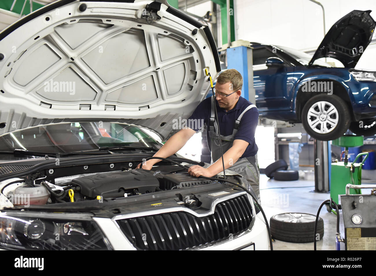 car mechanic checks the engine of a vehicle - in the background car on ...