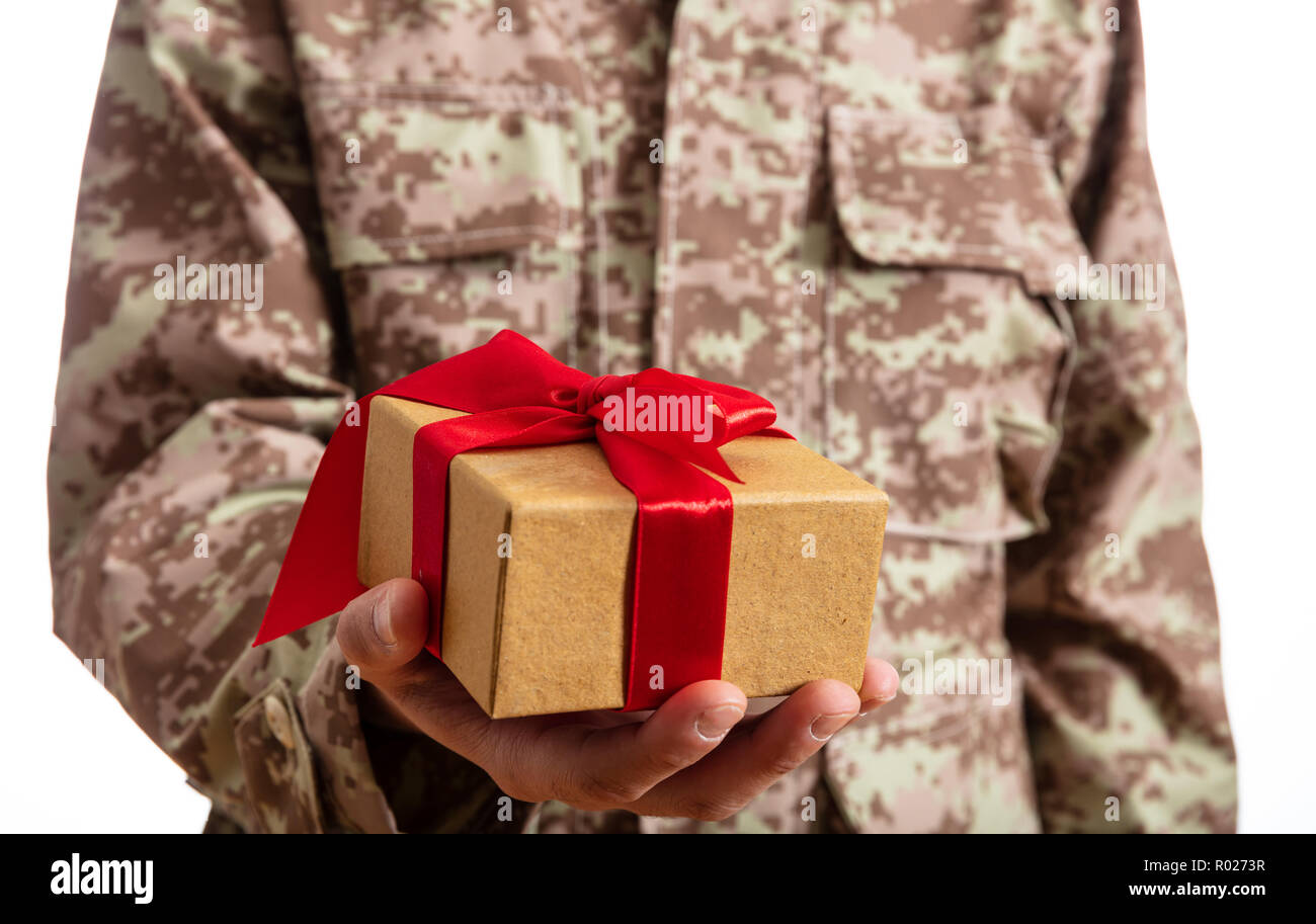 Christmas and Army. Young soldier holding a christmas gift standing on ...