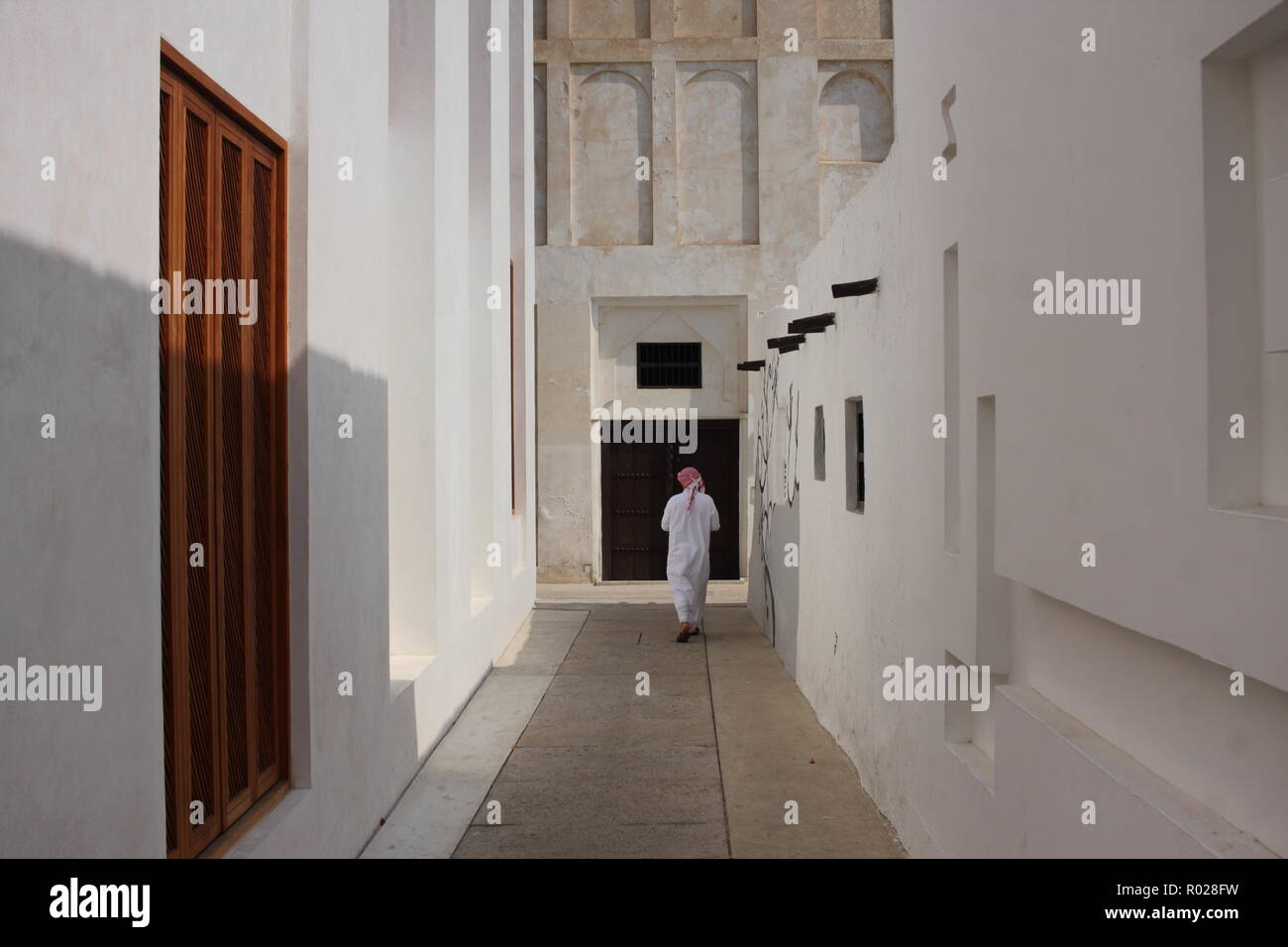 A Bahraini man wearing dishdash, guthra, and aghal walking along a ...