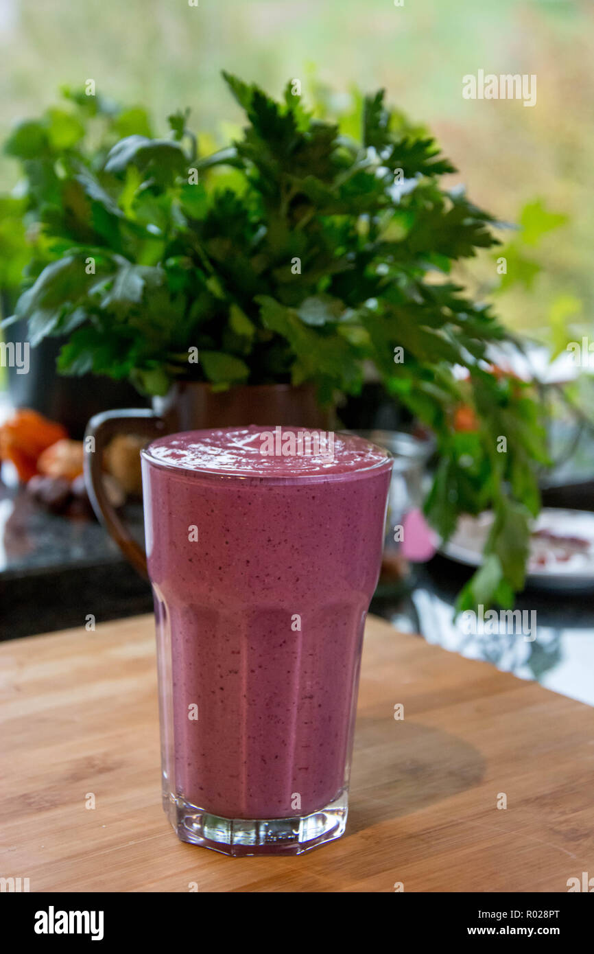 pink berry smoothie in kitchen with green parsley in background Stock ...
