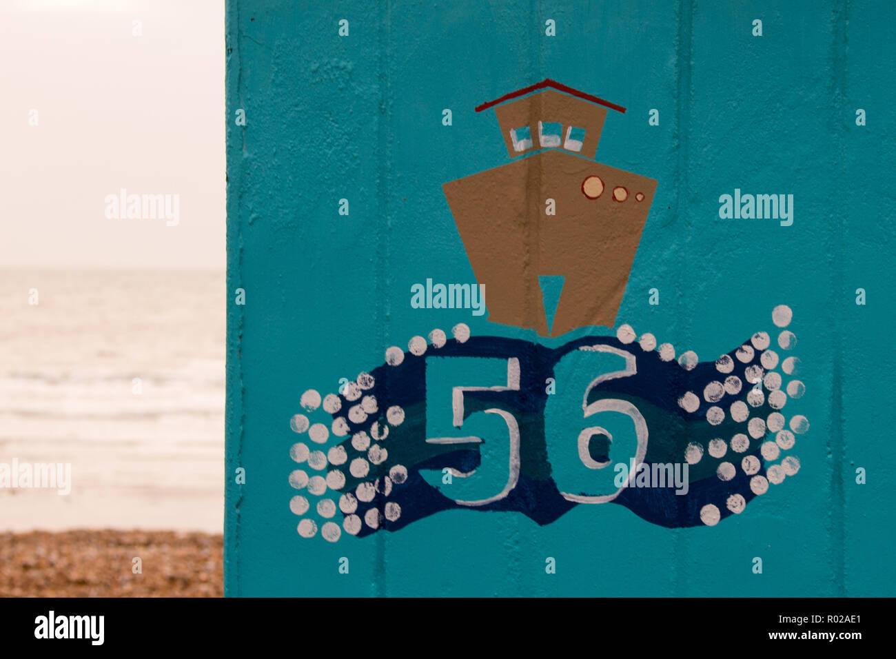 Brown painted boat on on a blue english beach hut with the number 56 ...