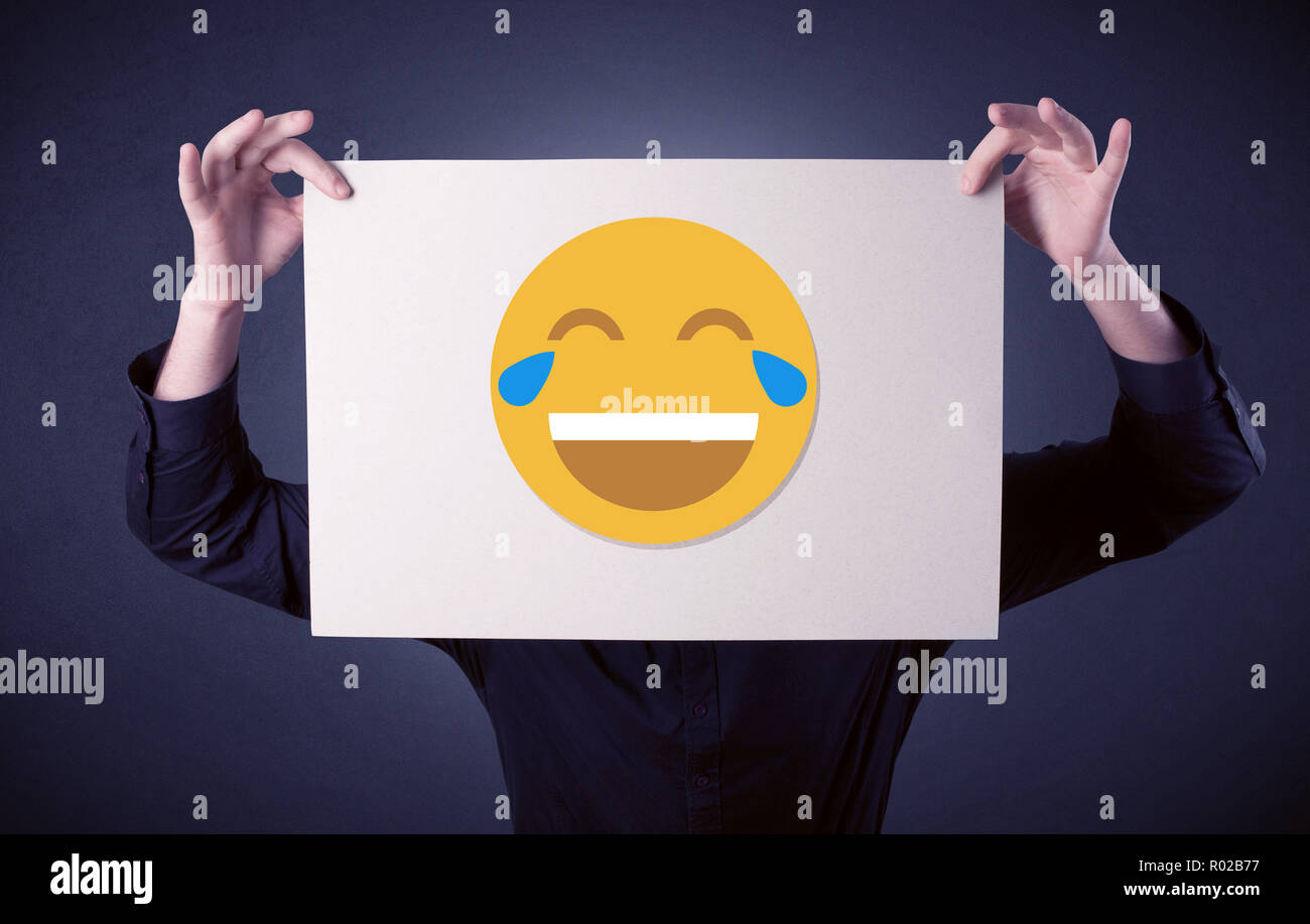 Young businessman hiding behind a laughing emoticon on cardboard Stock ...