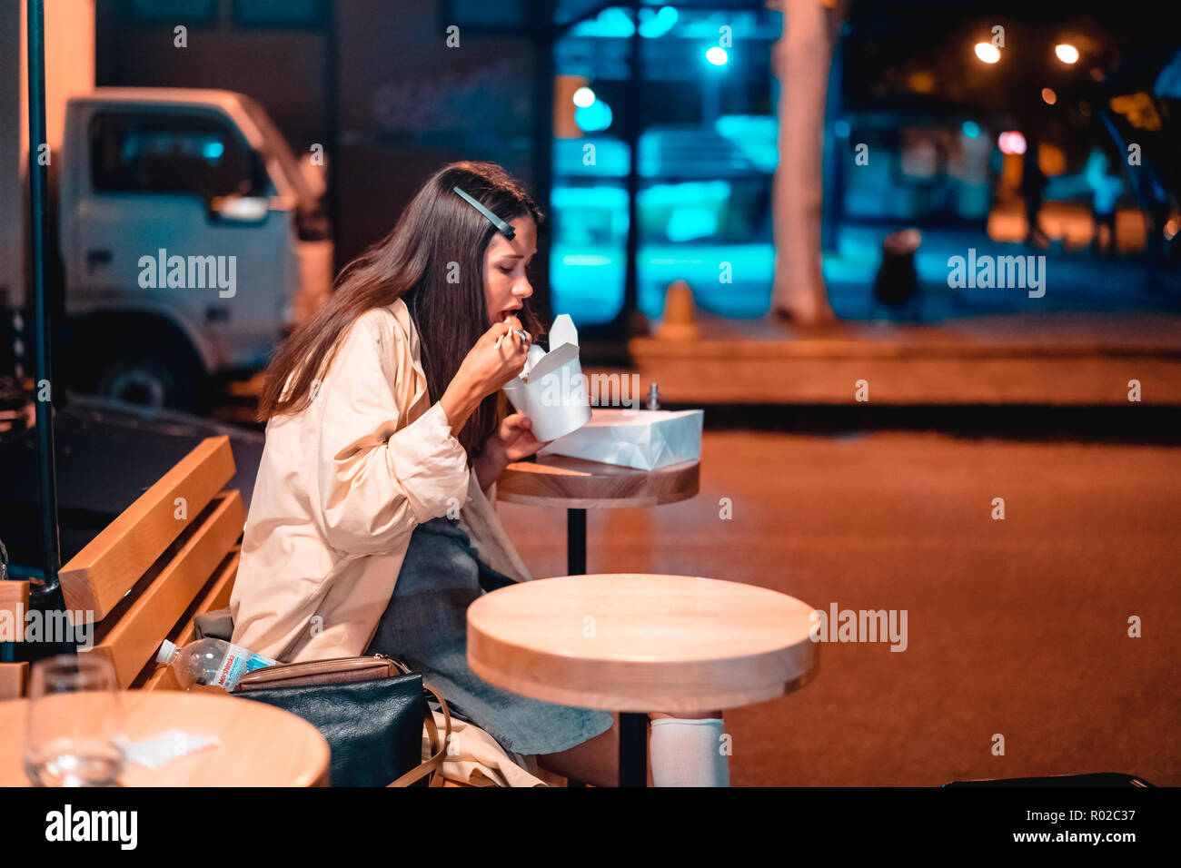 The girl is eating fast food, on the street of the night city Stock ...