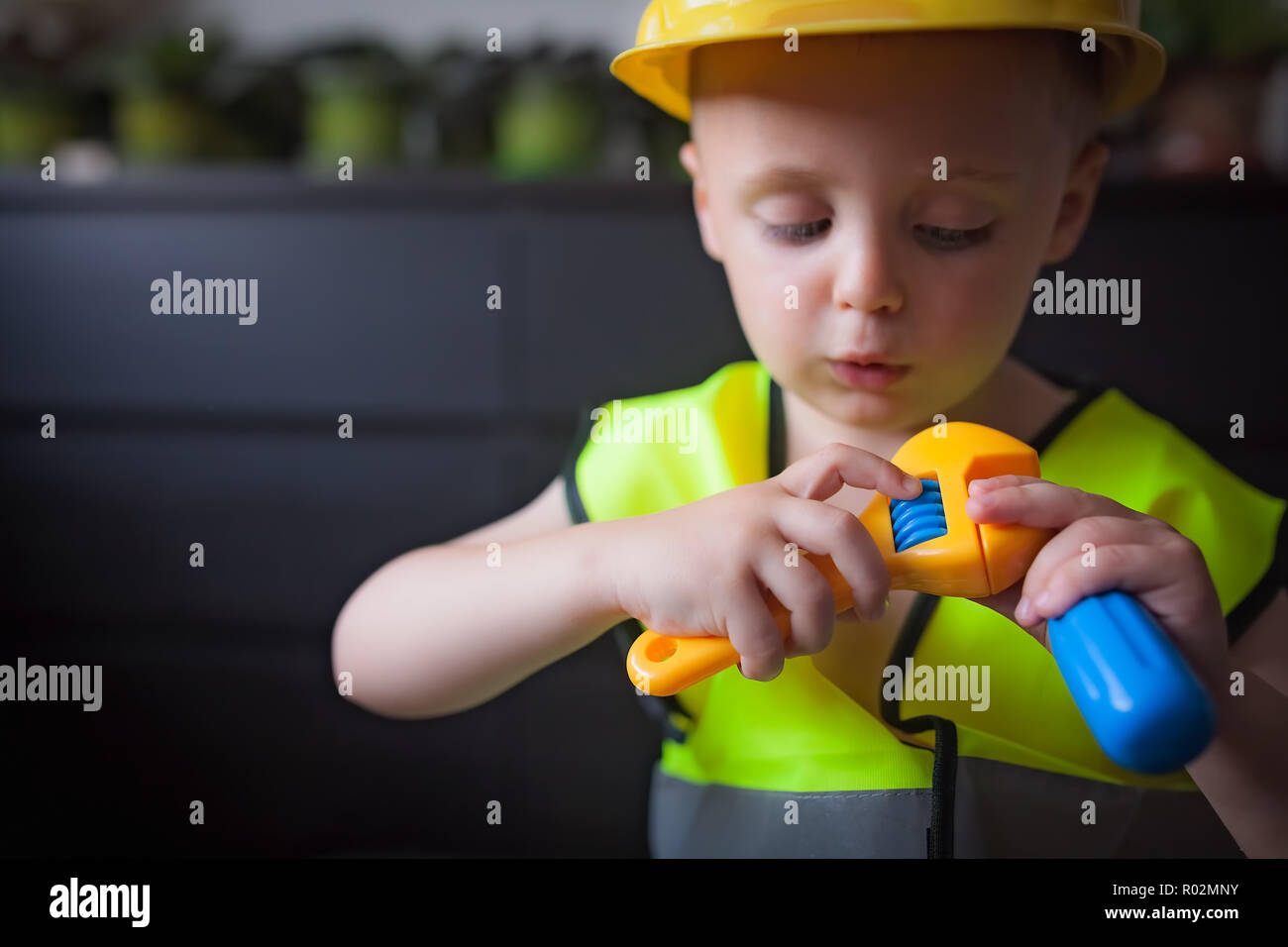 Little cute boy holding plastic toy tools pretending to be a builder ...