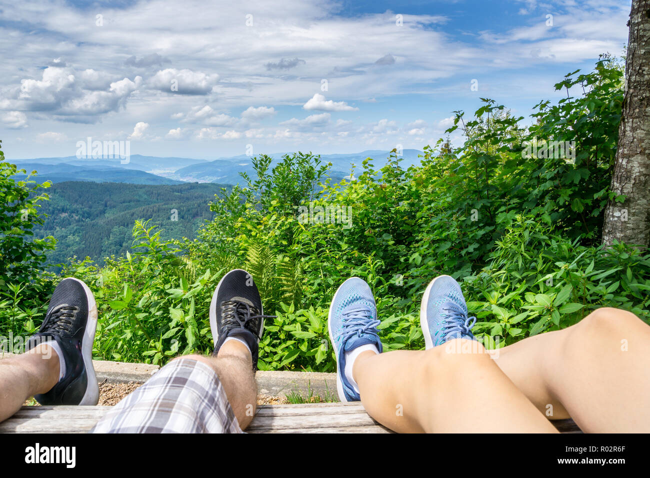 Legs of couple resting on top of black forest mountain enjoying ...