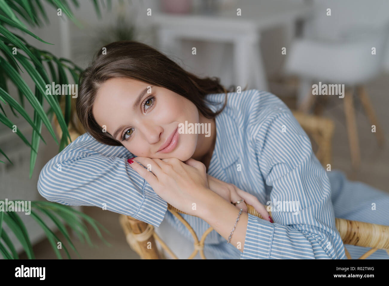 Image of good looking young female model with dark hair, sits on wooden ...