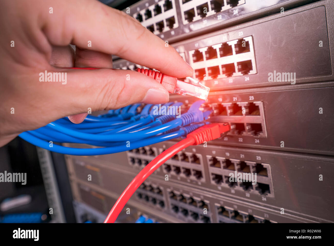 man working in network server room with fiber optic hub for digital ...