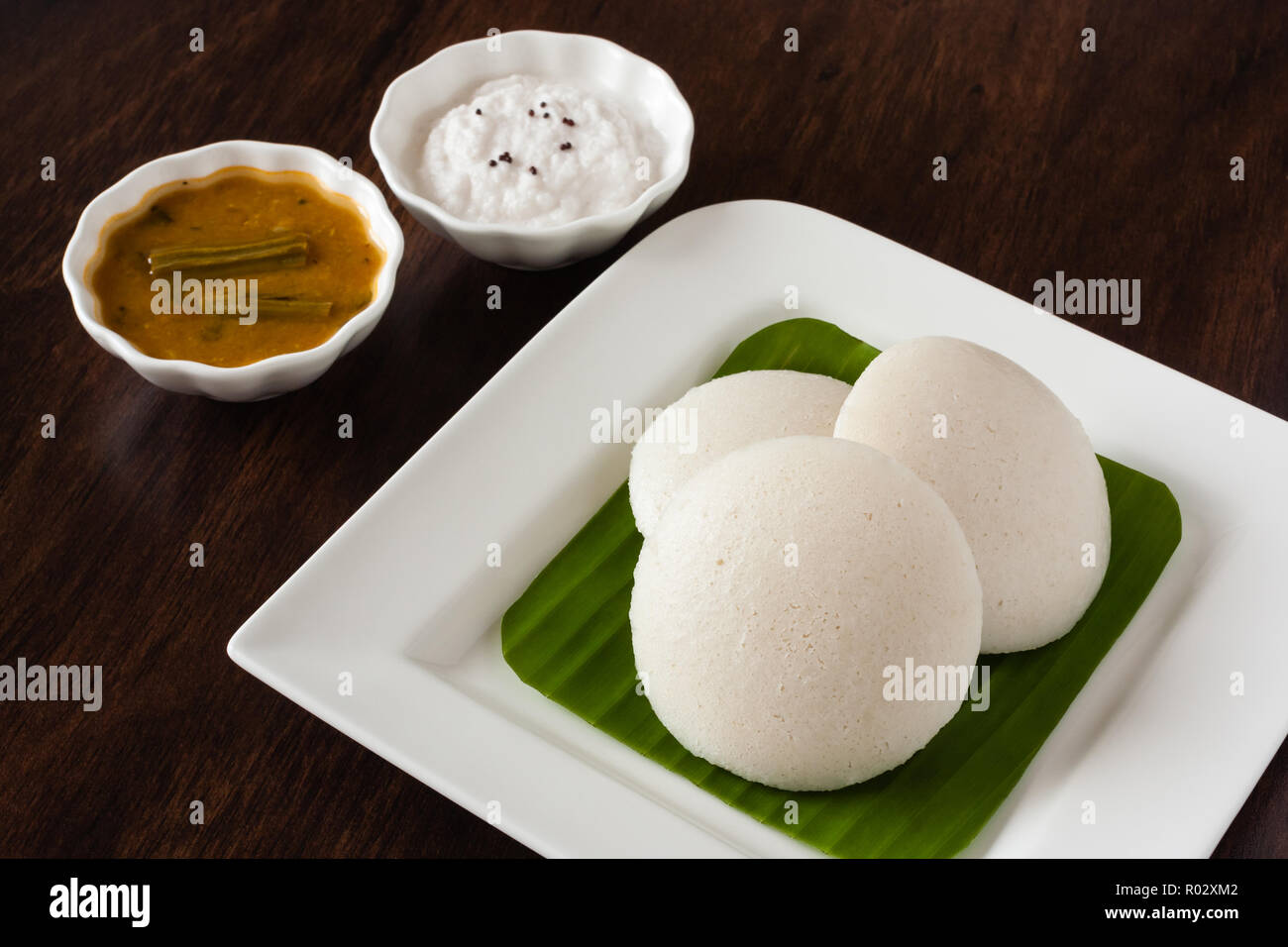 Fresh steamed Indian Idly (Idli / rice cake) arranged on banana leaf ...