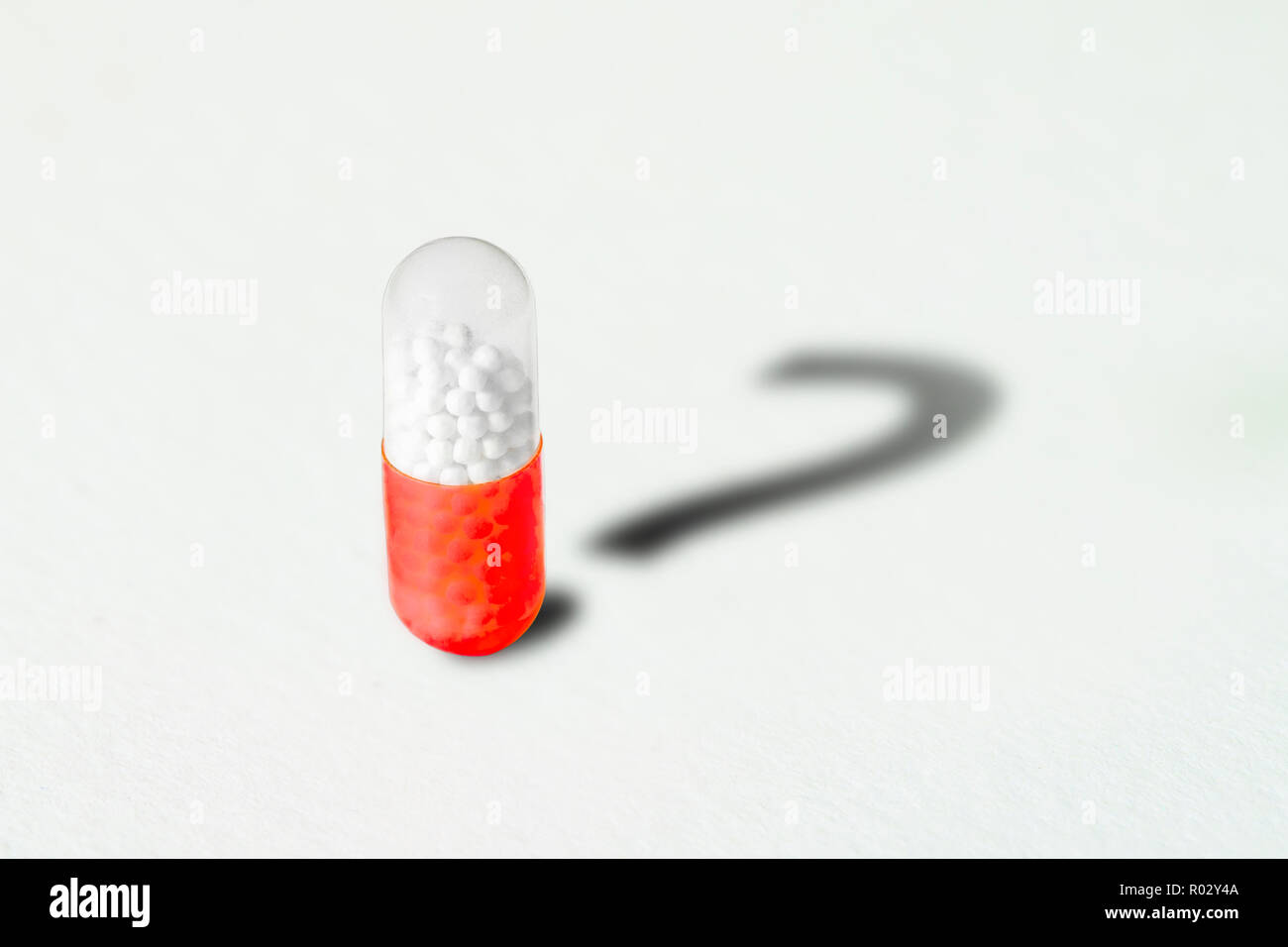 Pill and shadow in the form of a question mark on a white background ...
