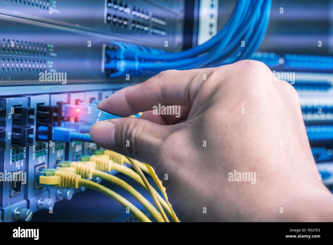 man working in network server room with fiber optic hub for digital ...