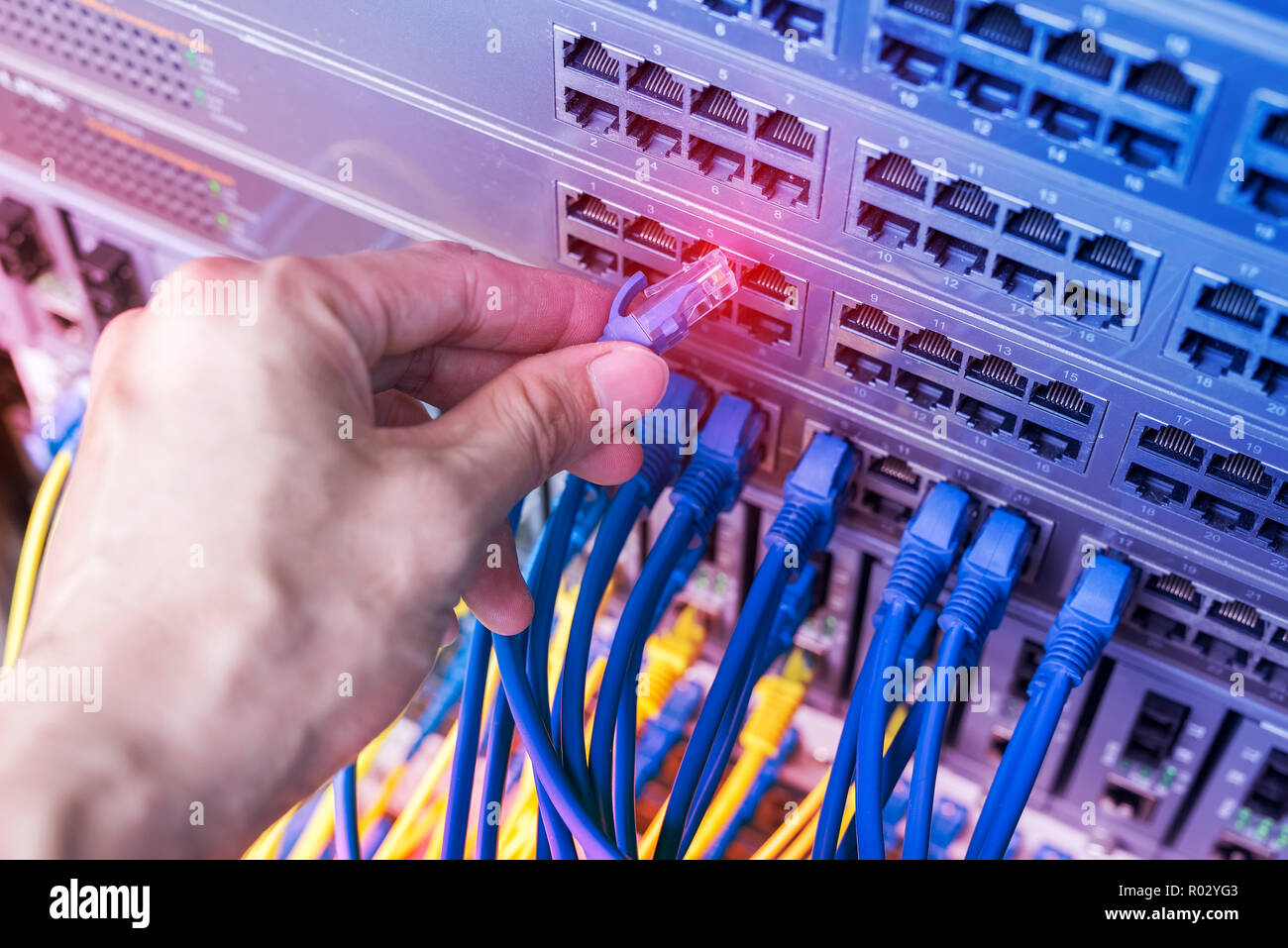man working in network server room with fiber optic hub for digital ...
