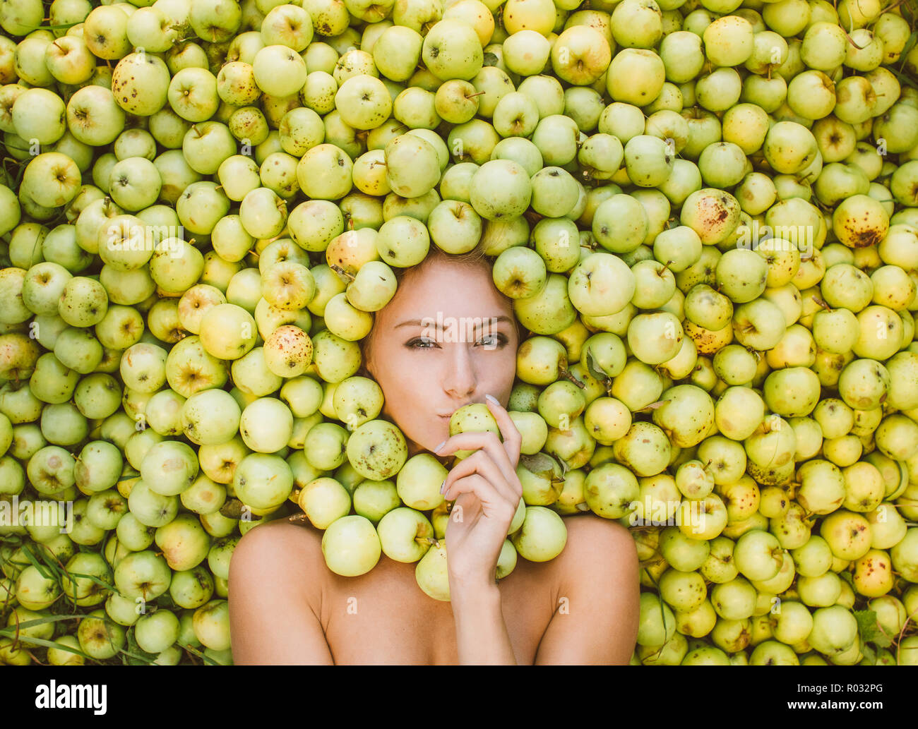 Portrait of beautiful girl that lies in the green apples, apples near ...