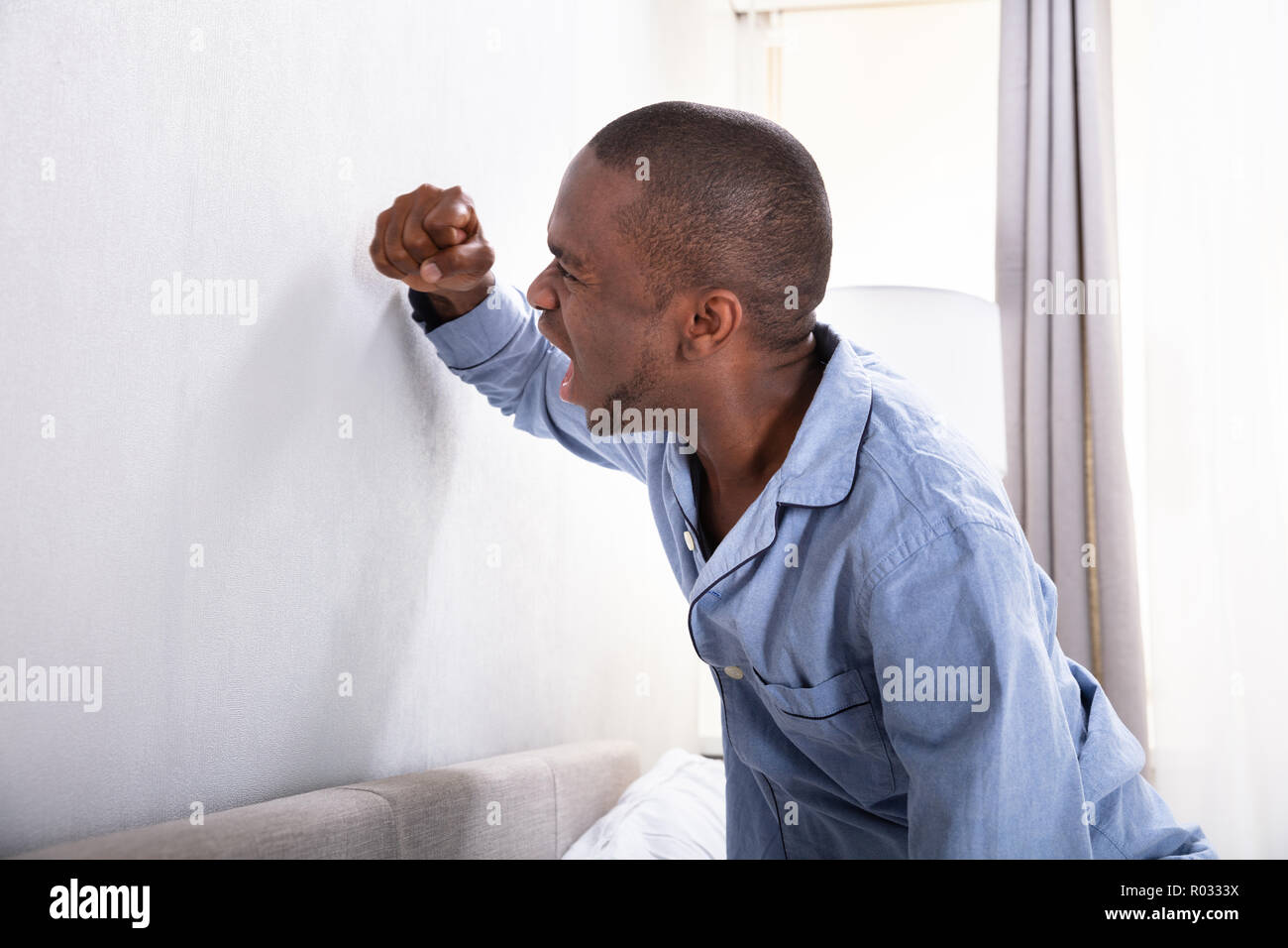 Aggressive Young Man Hitting Wall With His Fist Stock Photo - Alamy