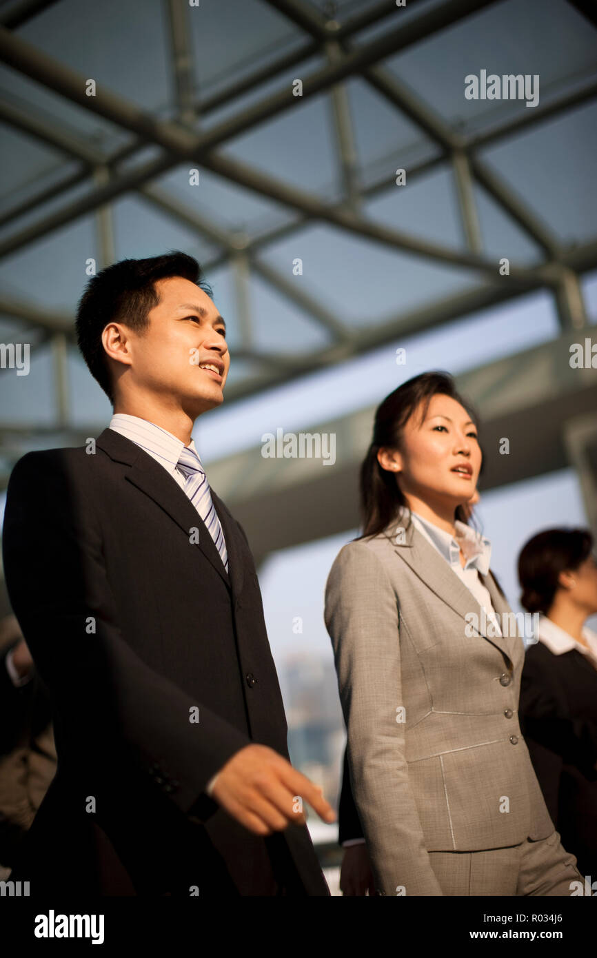 Three business colleagues walking together through an office building ...