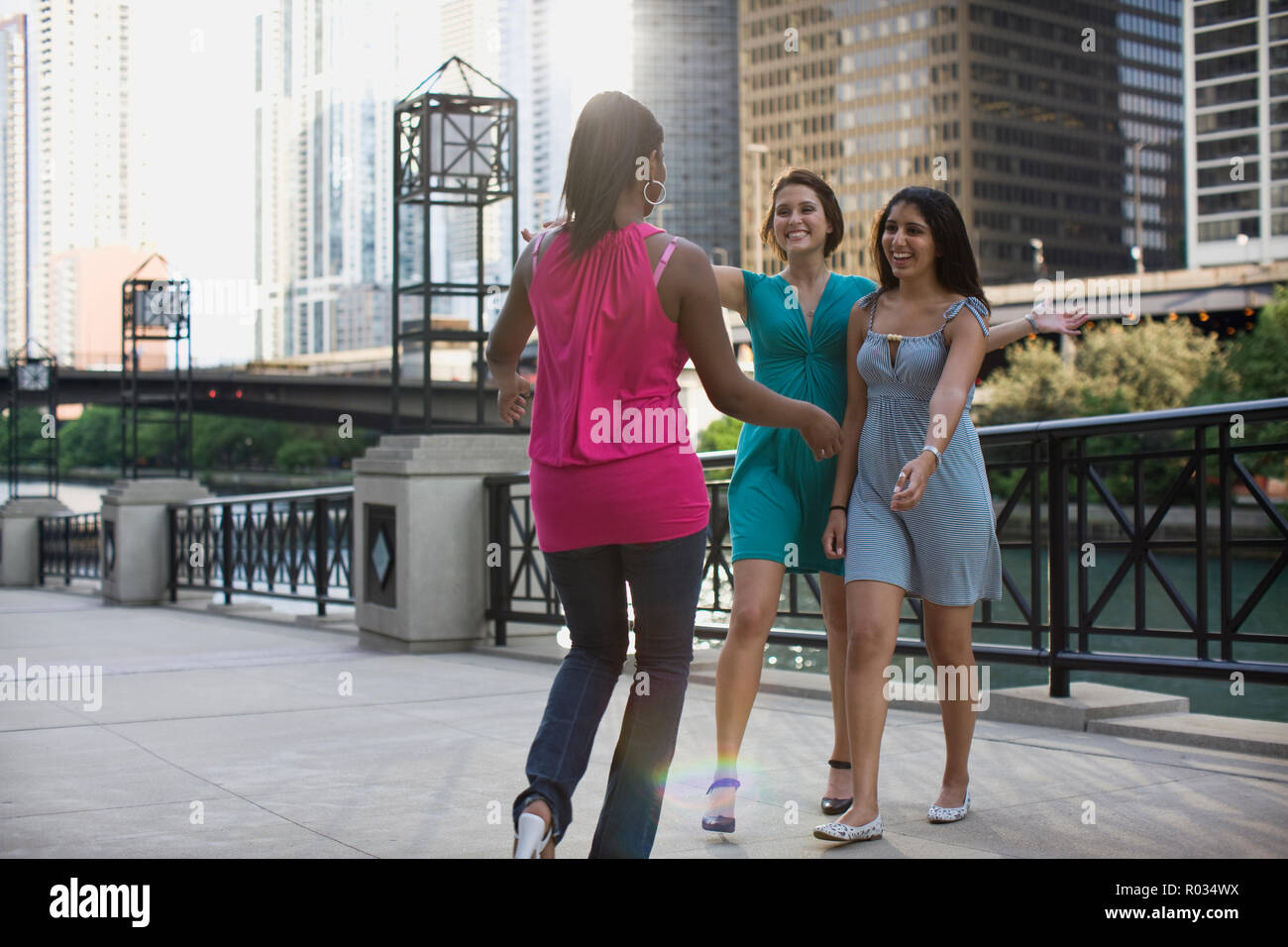 Two smiling friends reaching their arms out to hug another friend in ...