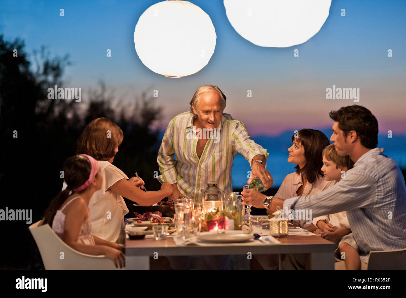 Family enjoying an outdoor dinner on their back deck Stock Photo - Alamy