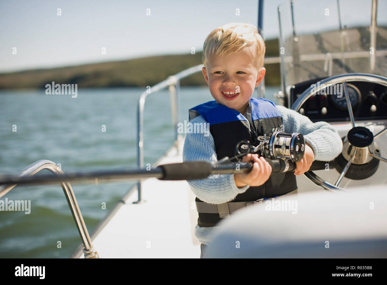 Little boy smiling and holding fishing rod Stock Photo - Alamy