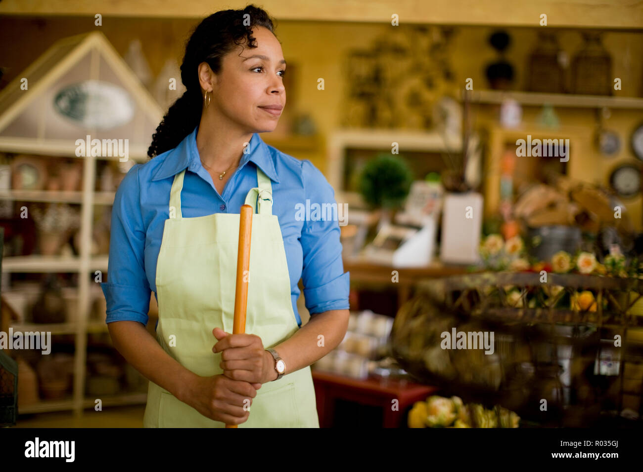 Sales clerk standing in store holding broom Stock Photo - Alamy
