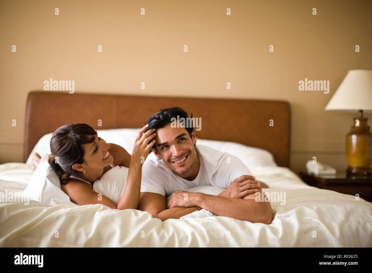 Couple lying on front in bed Stock Photo - Alamy
