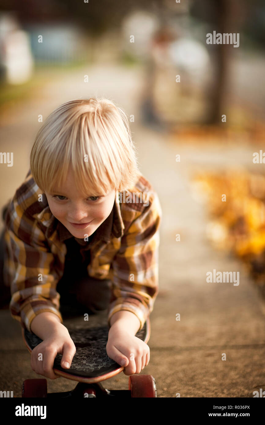 Boy pushing skateboard along footpath Stock Photo - Alamy