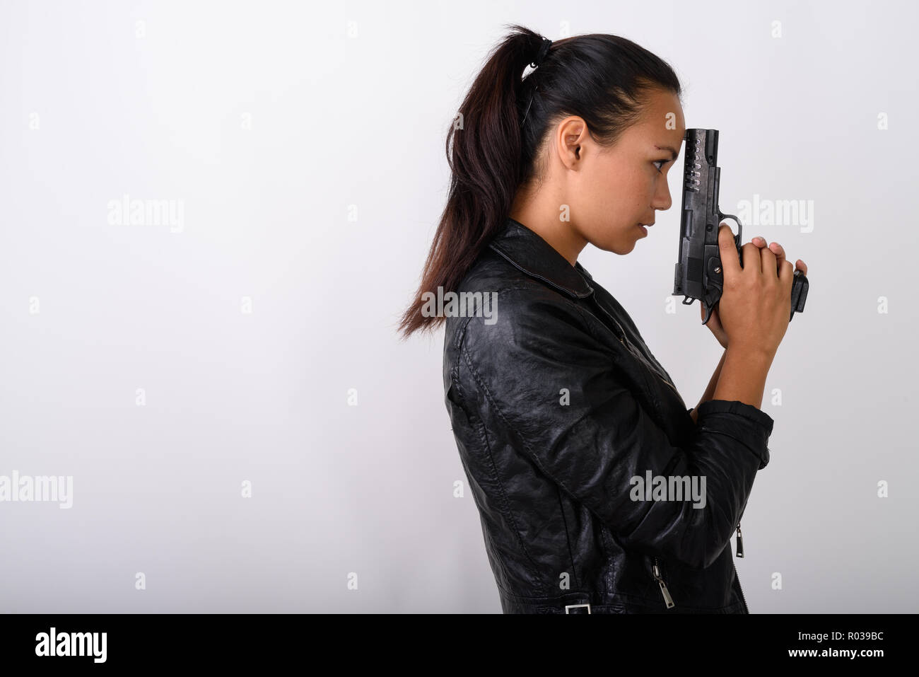 Profile view of young Asian woman holding handgun against white Stock ...