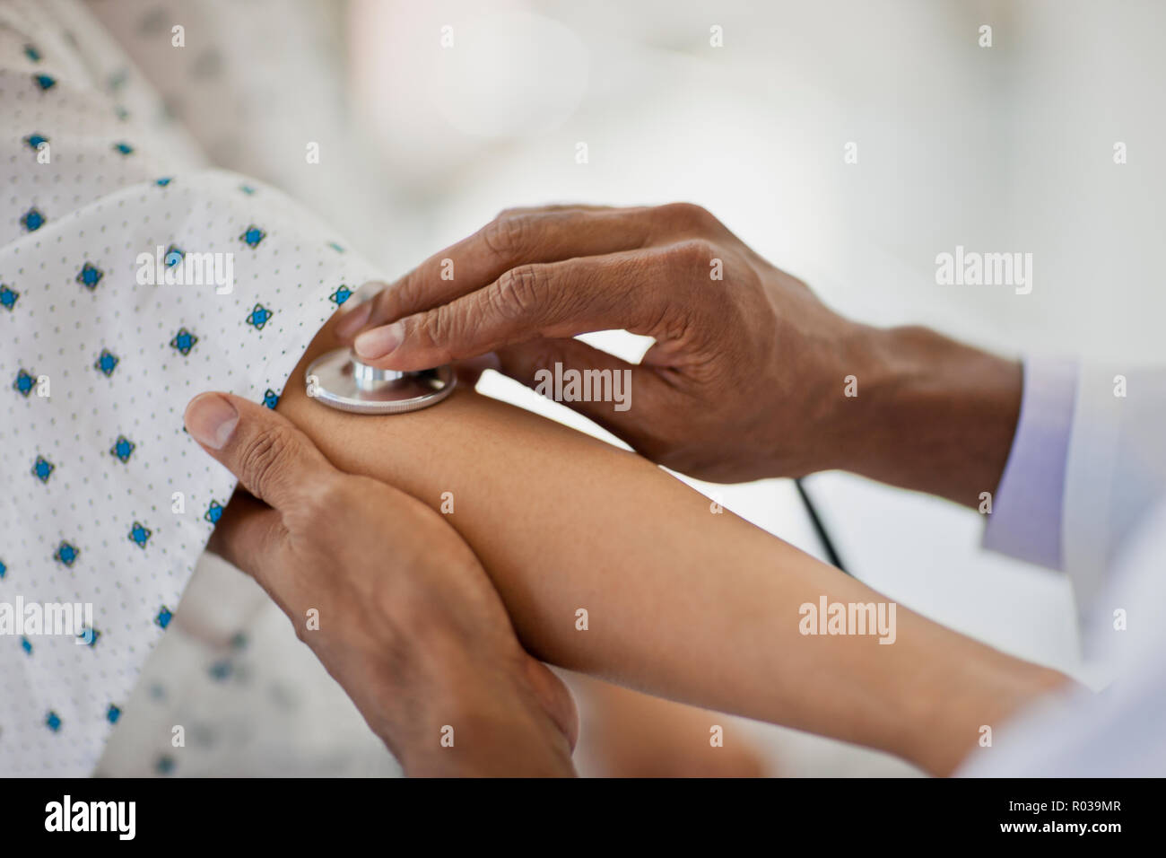 Doctor's hands placing a stethoscope on the inside of a patient's elbow ...