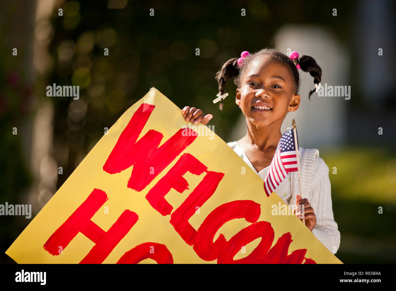 Young girl holding an American flag and a welcome home sign Stock Photo ...