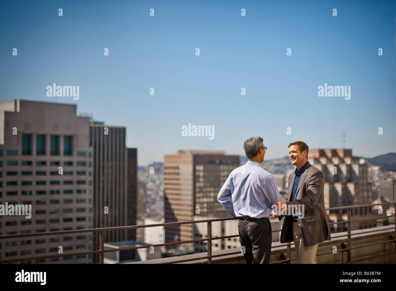 Businessmen talking on an office balcony Stock Photo - Alamy