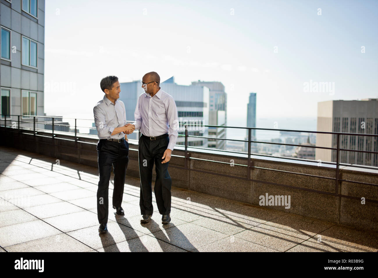 Businessmen shaking hands on balcony Stock Photo - Alamy