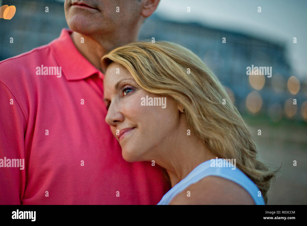 Woman lovingly resting her head on her husband's chest as they watch ...