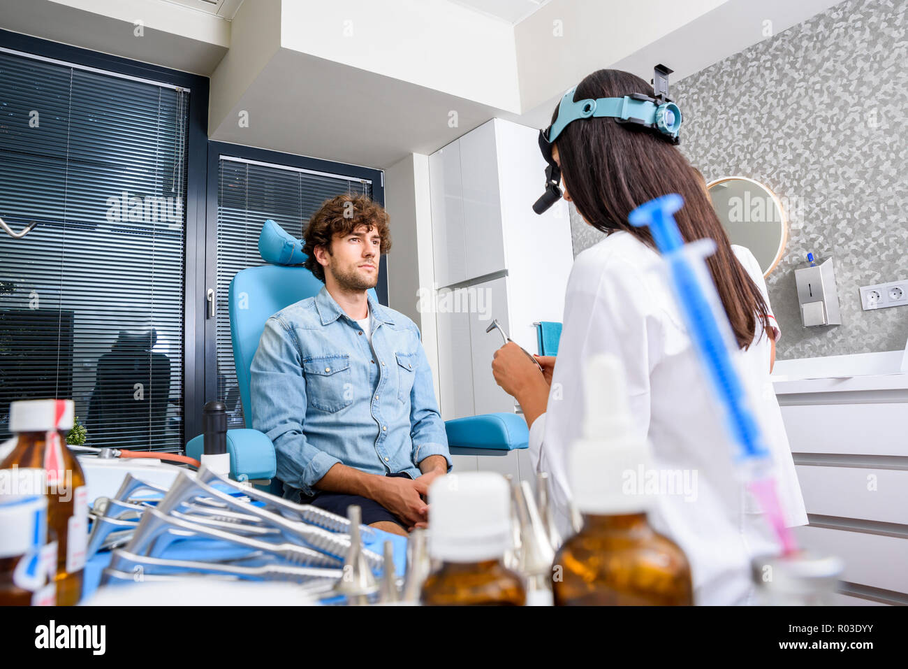 A female Ear-Nose-Throat aka ENT specialist doctor diagnosing a young ...