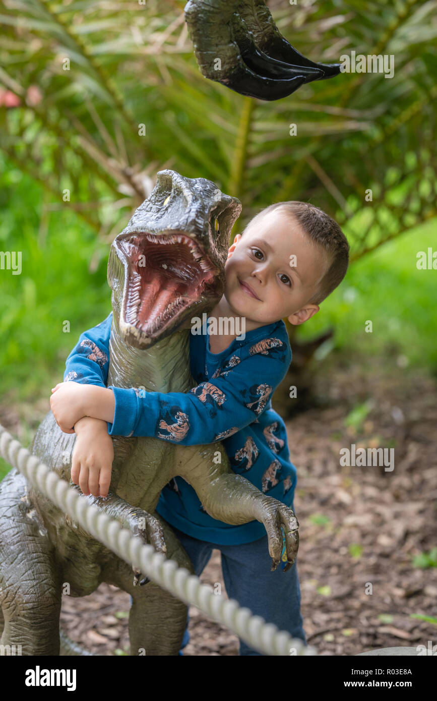 Little cute Caucasian boy hugging small raptor replica figure in an ...