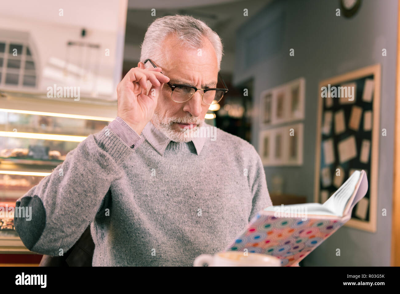 Smart bearded man feeling emotional after reading scientific book Stock ...