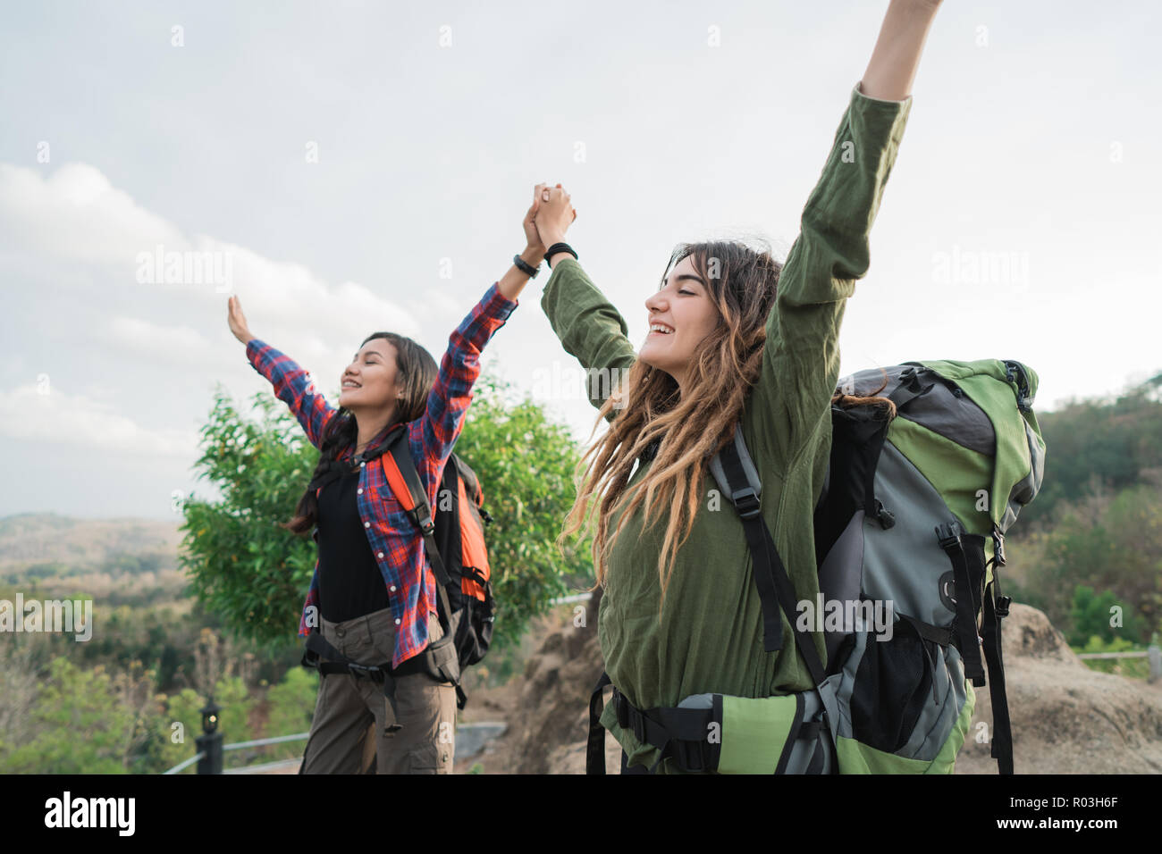 happy two young hiker friends smiling after reaching to the top of the ...
