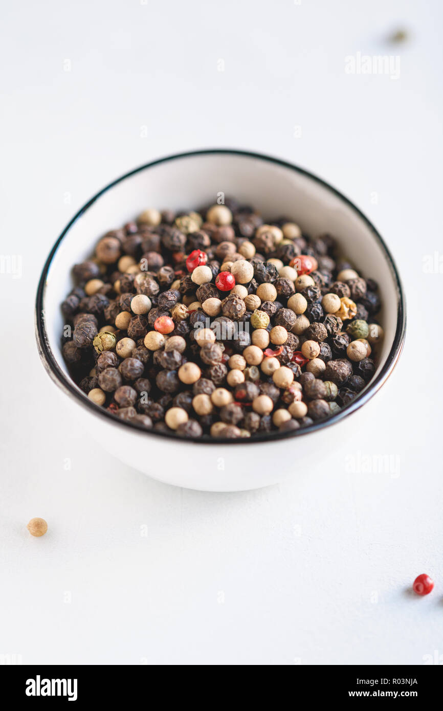 Various kinds of pepper seeds in a white bowl on a white background ...