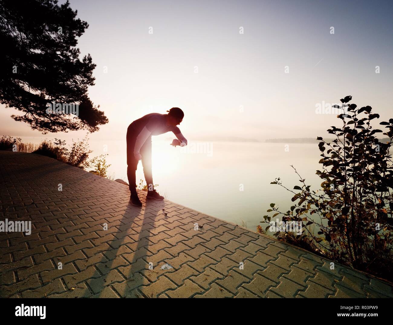 Runner check watches within little break. Sportsman jogging in evening ...