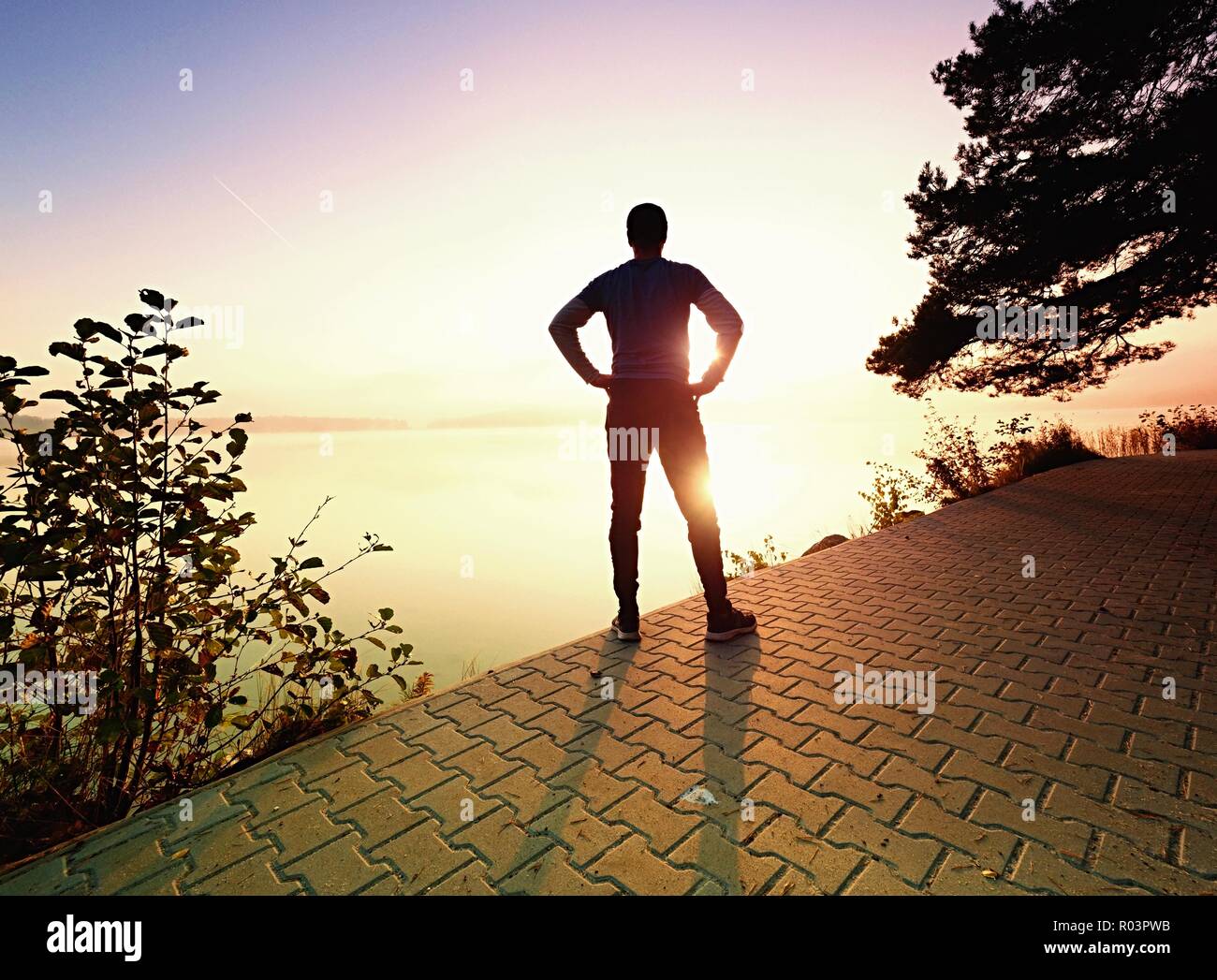 Active sport man runner stretching body on pavement lake side, regular ...