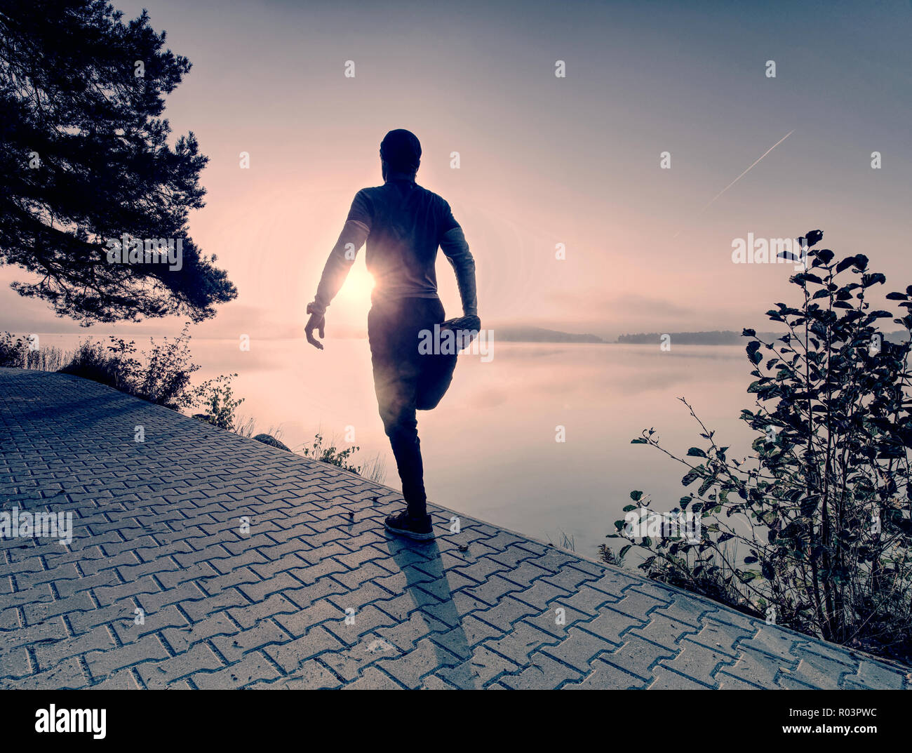 Runner sprints along lake. Freeze sportsman in running pose. Morning ...