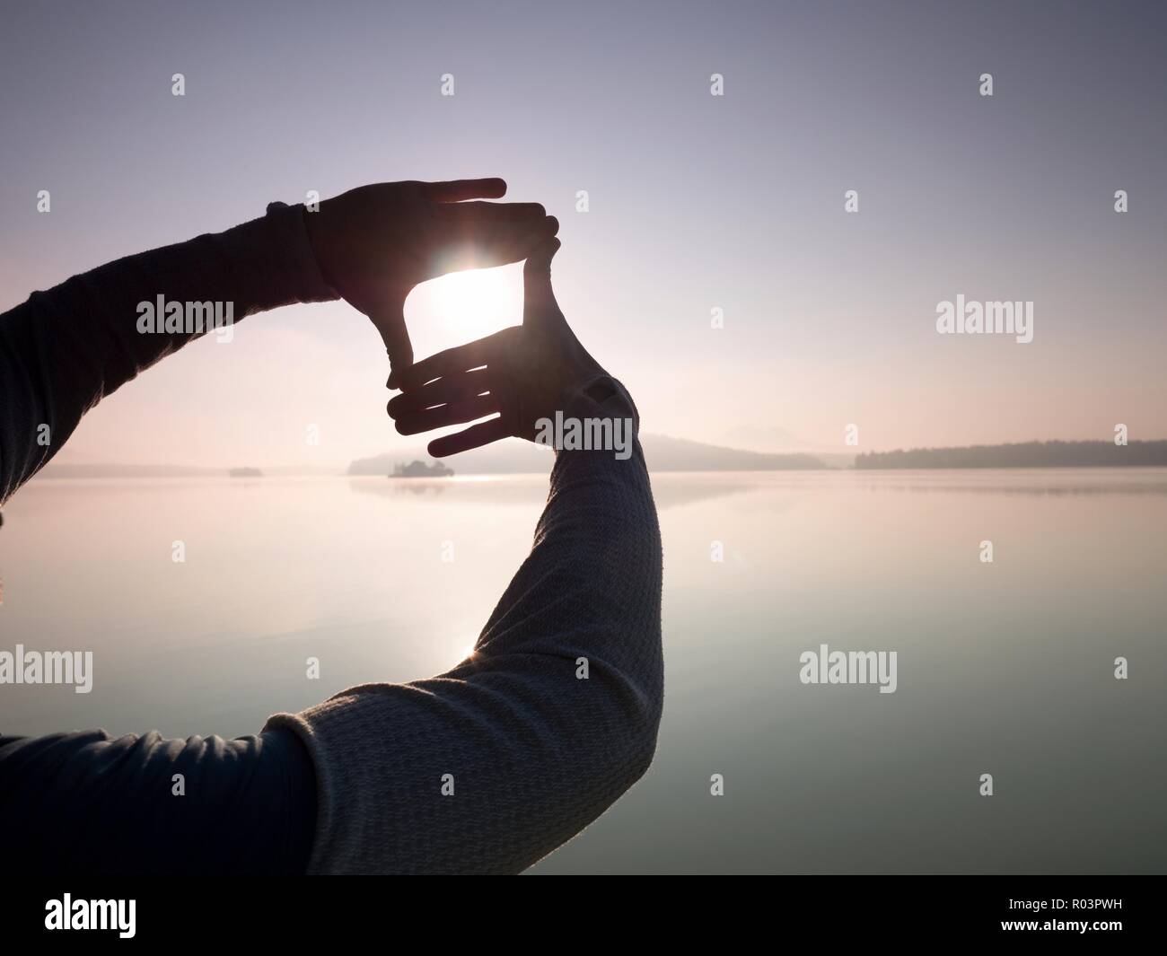 Fingers gesturing picture frame on sunrise seaside. Sunlight on beach ...