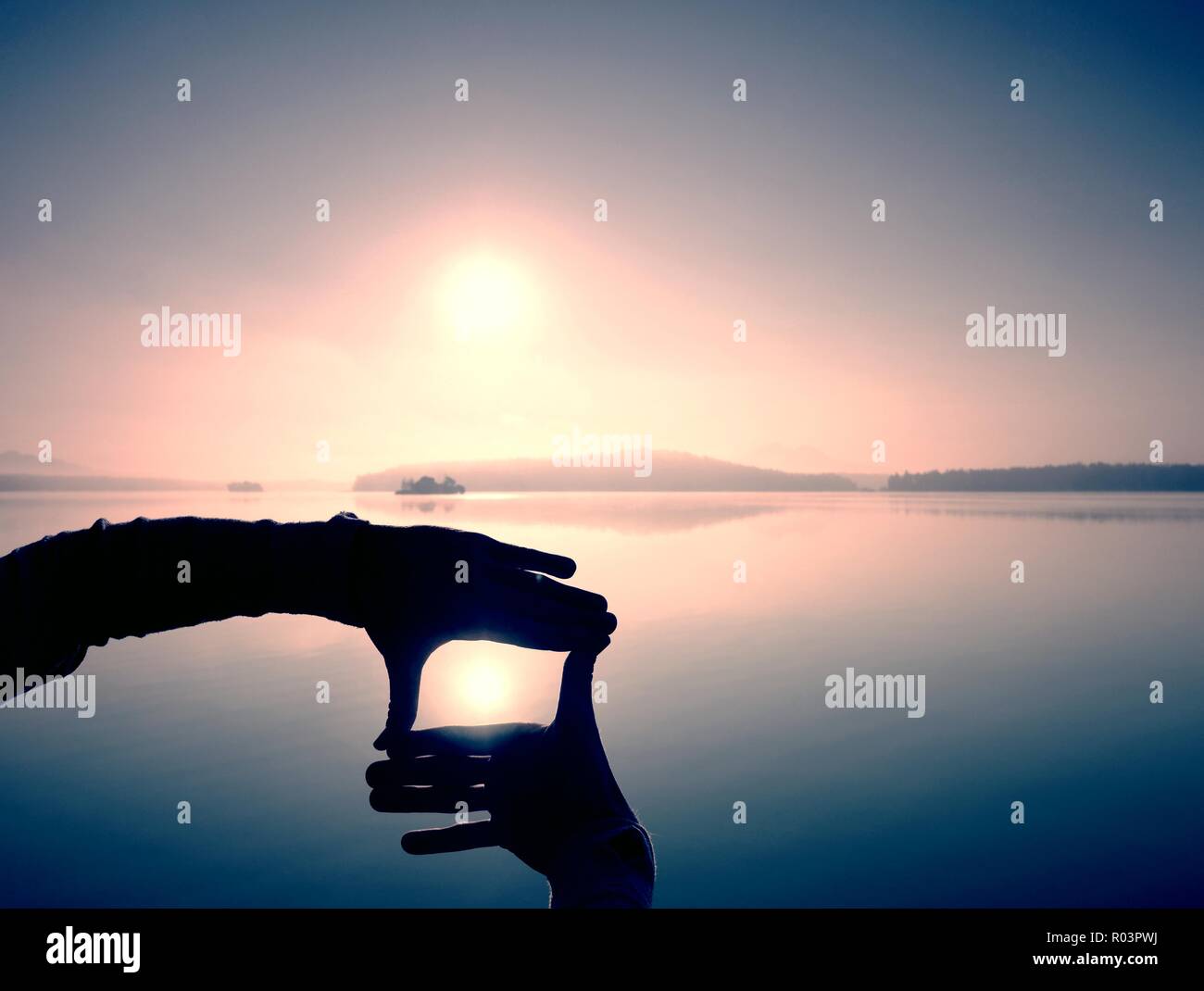 Fingers gesturing picture frame on sunrise seaside. Sunlight on beach ...