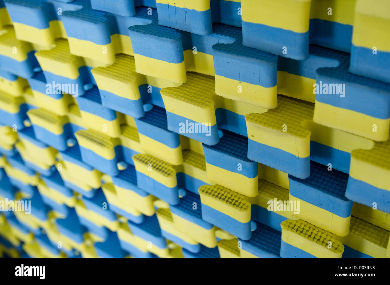 blue-yellow sports mats stacked in large stack Stock Photo - Alamy