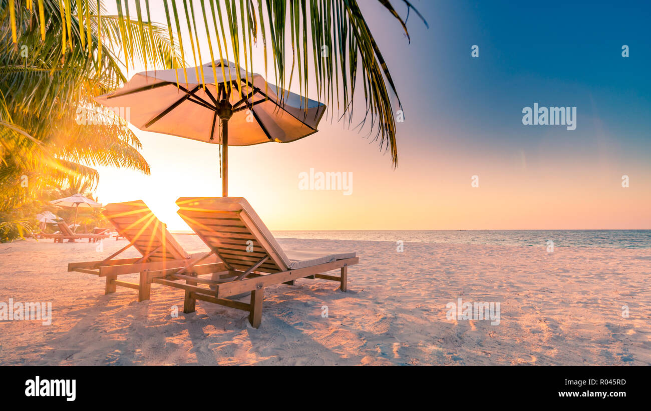 Beautiful tropical sunset scenery, two sun beds, loungers, umbrella ...