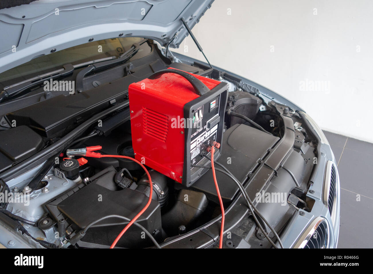 Car engine space with bonnet up and battery on charge with broken down ...