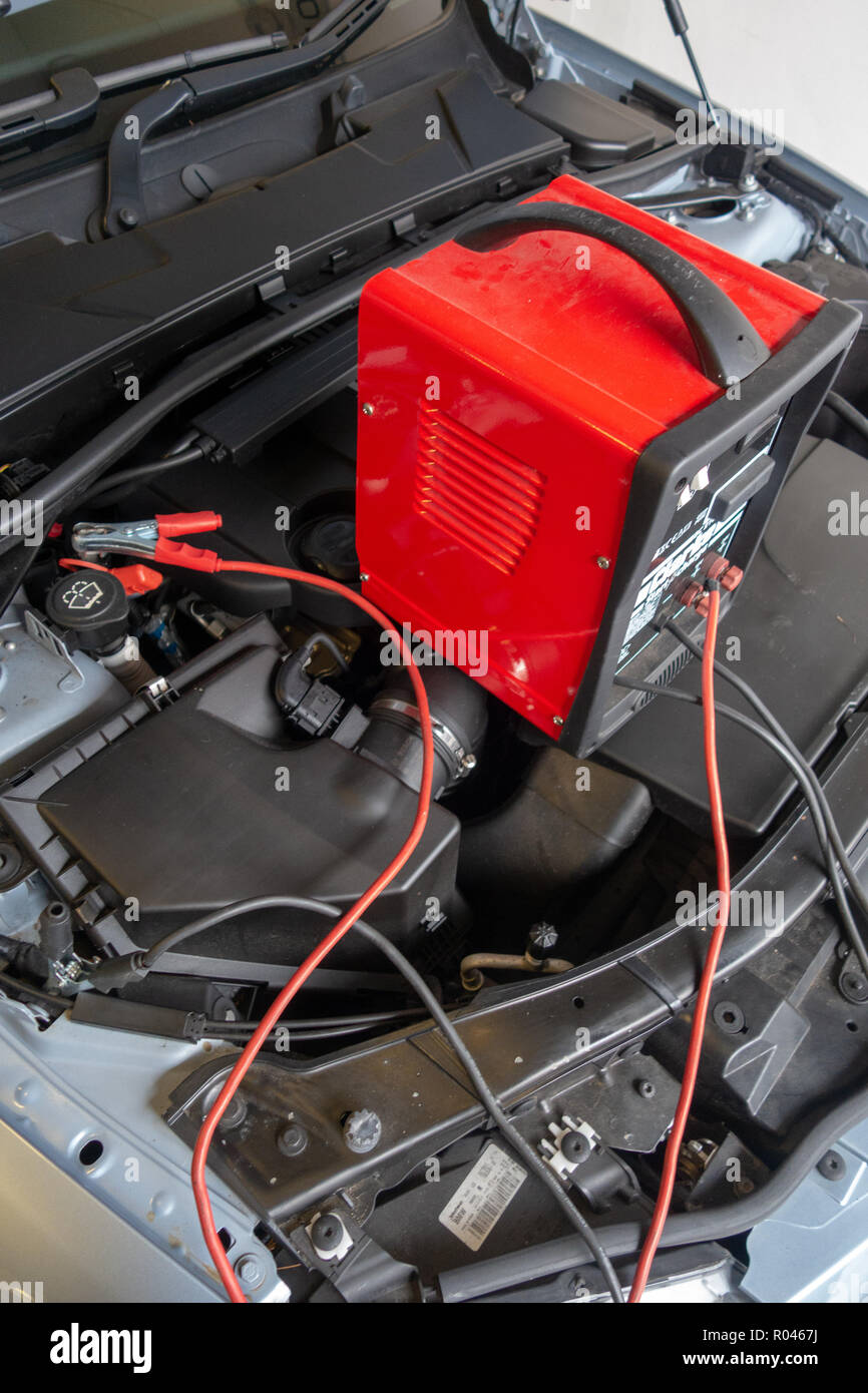 Car engine space with bonnet up and battery on charge with broken down ...