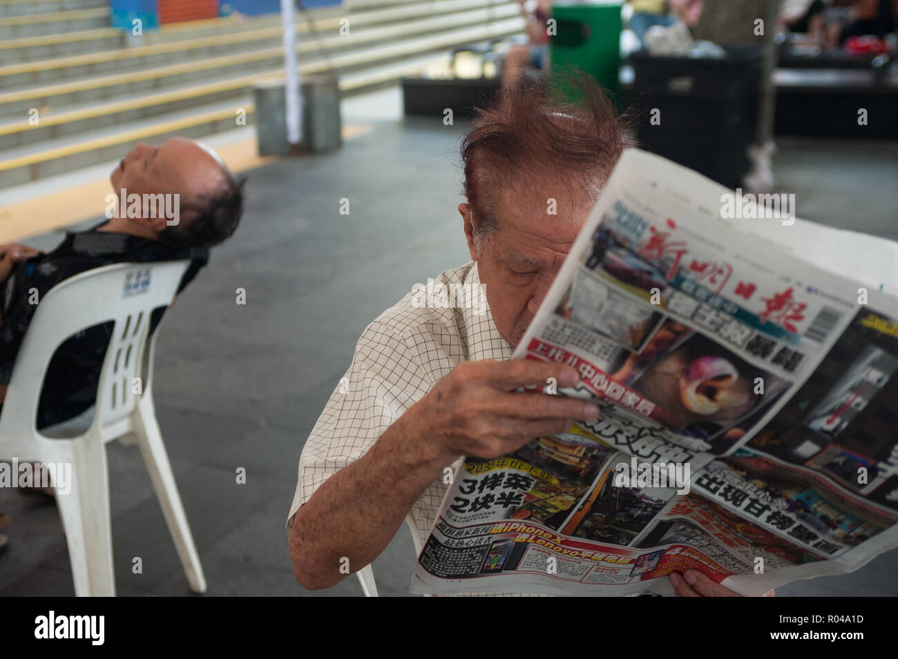 Republic of Singapore, man reads newspaper in Chinatown Stock Photo - Alamy