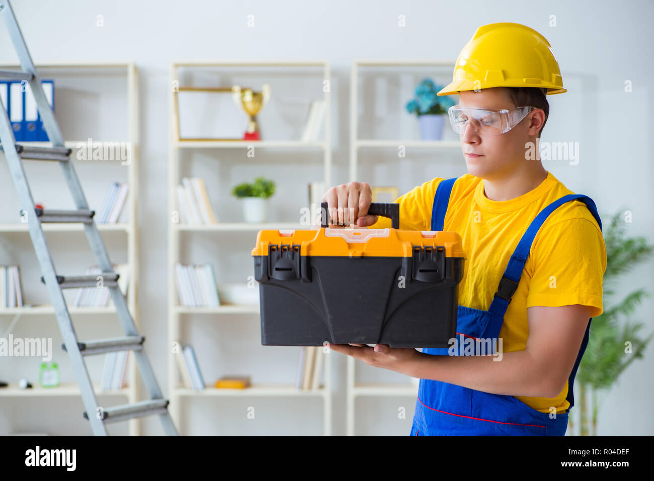 Young contractor doing repair works at office Stock Photo - Alamy